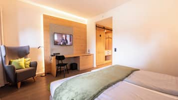 Quarto de hotel moderno com cama, escrivaninha, cadeira e televisão.