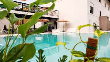 Piscina interna com vista para um edifício com varandas e área de estar ao ar livre.