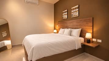 Quarto de hotel moderno com uma cama grande, mesas de cabeceira com luminárias e obras de arte nas paredes.