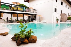 Piscina interna com superfície de água cristalina, cercada por pedras e plantas em vasos.