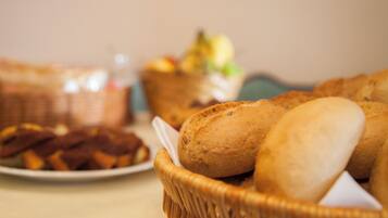 Uma mesa com diversos alimentos, incluindo pão e doces, dispostos sobre uma toalha.