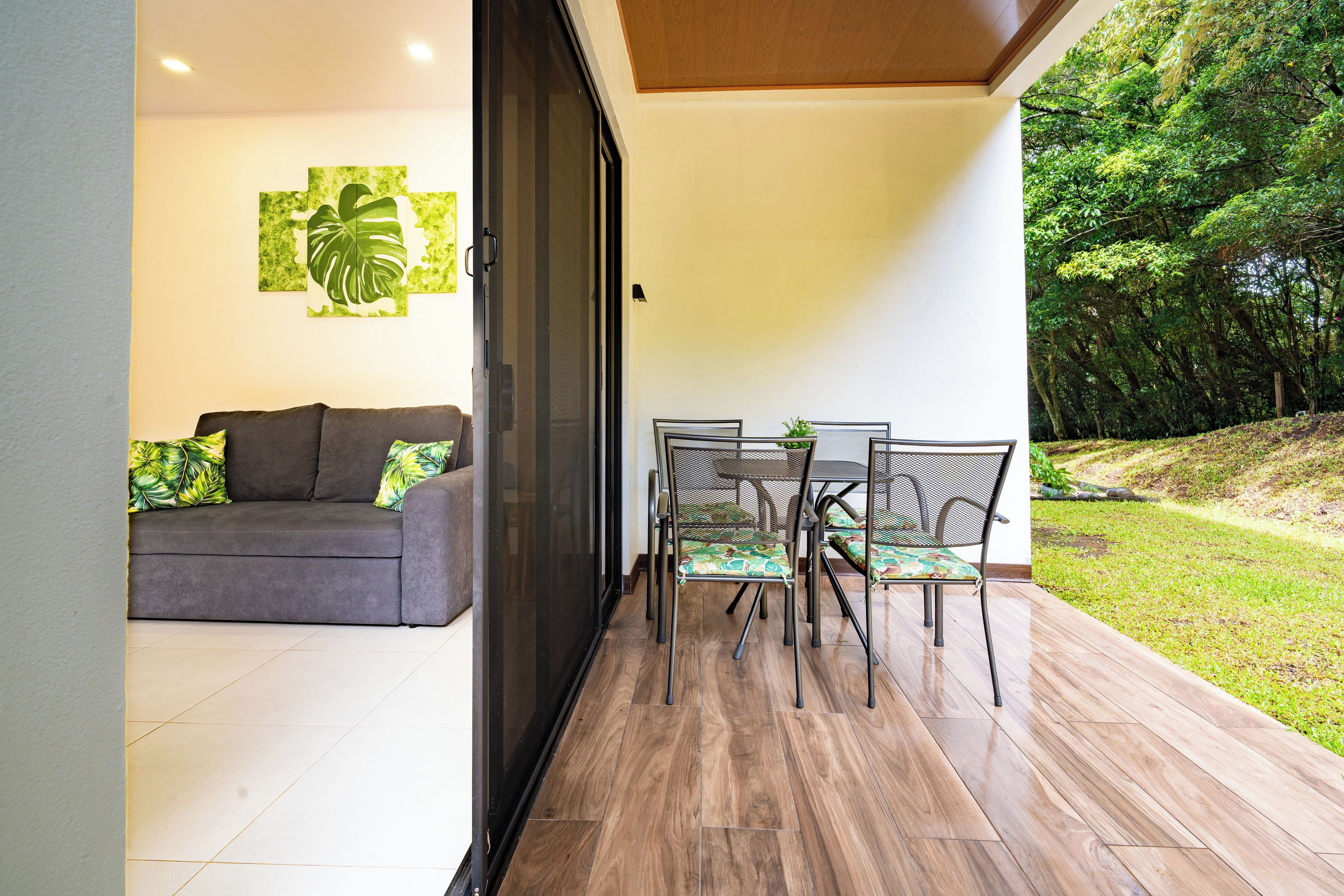 Uma sala de estar moderna com sofá, mesa de jantar com cadeiras e uma grande janela com vista para um jardim.
