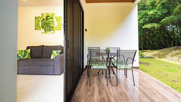 Uma sala de estar moderna com sofá, mesa de jantar com cadeiras e uma grande janela com vista para um jardim.