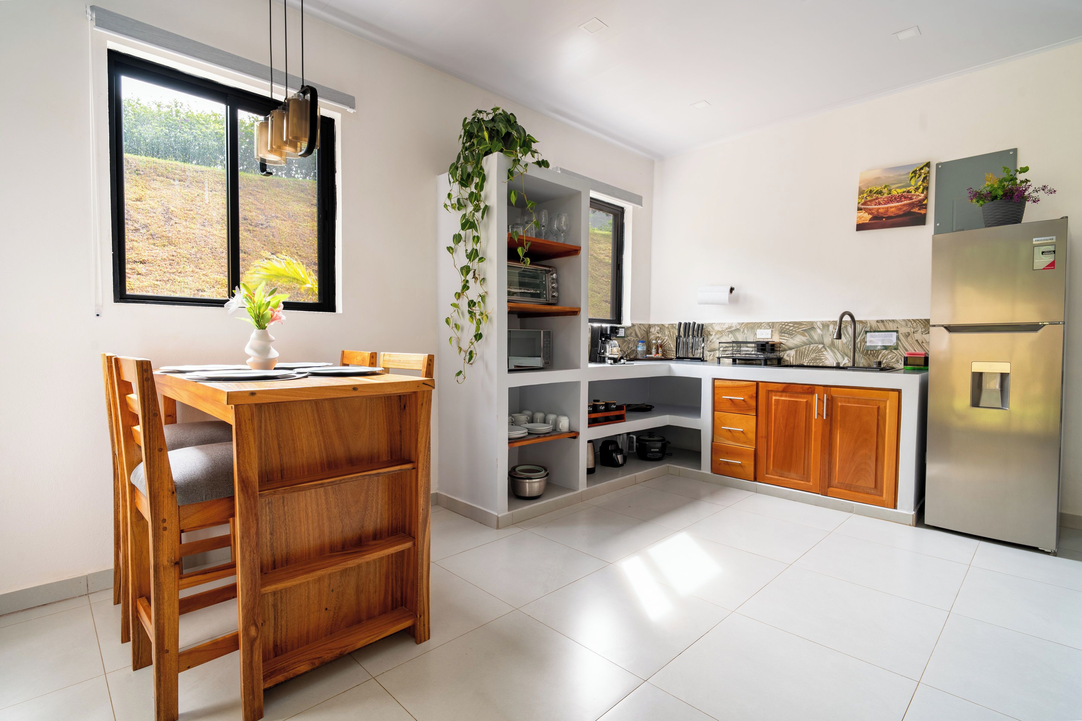 Uma cozinha moderna com armários de madeira, uma geladeira de aço inoxidável e um espaço de refeições com mesa e cadeiras de madeira.