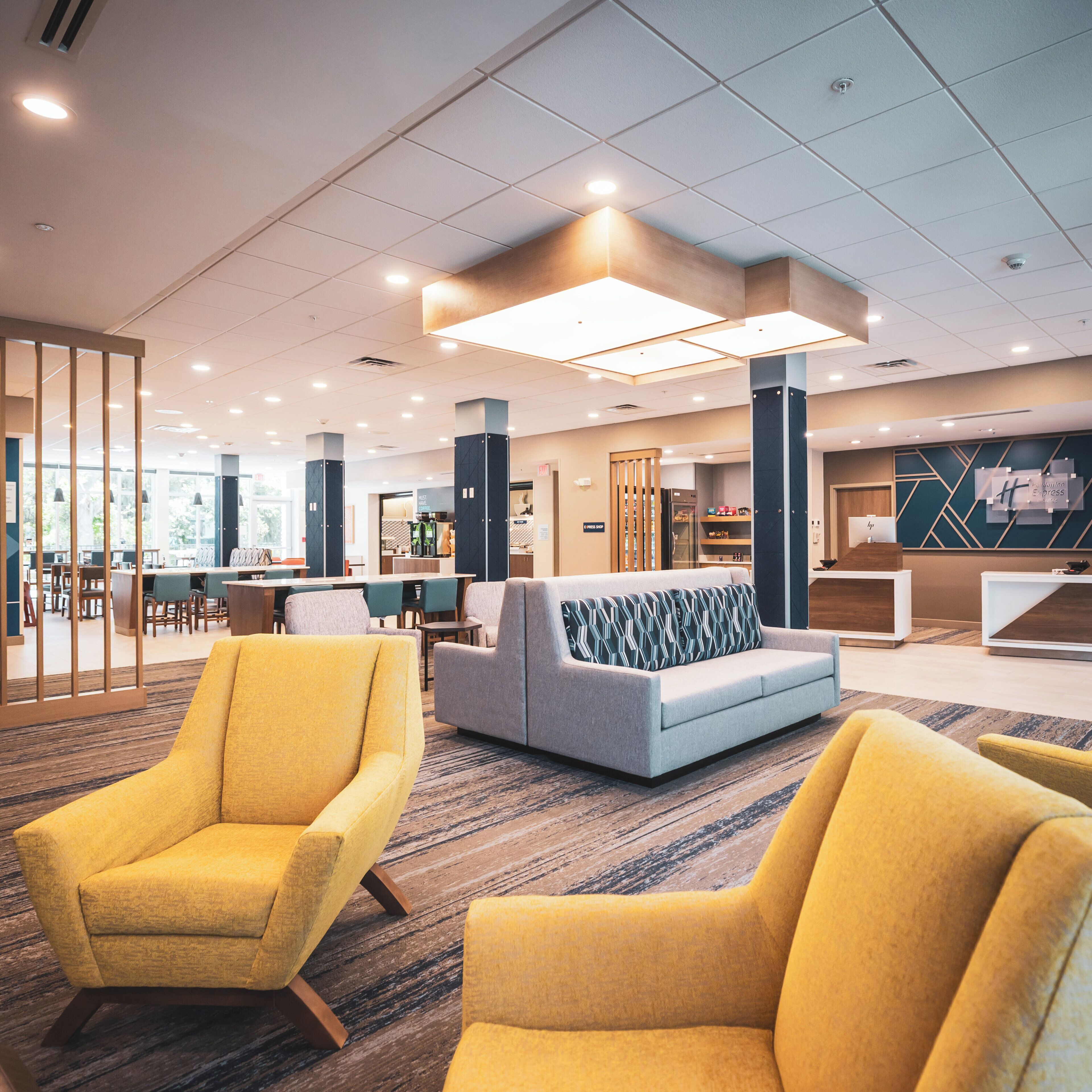 Um lobby moderno com áreas de estar, balcão de recepção e café.