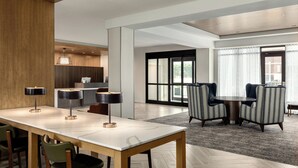 Quarto de hotel moderno com área de refeições, cozinha e uma janela ampla.