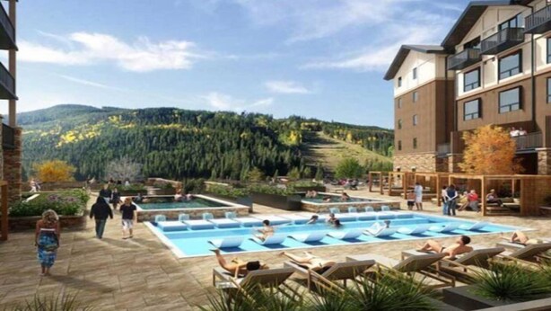 Uma área de piscina com várias piscinas e espreguiçadeiras, rodeada por edifícios e uma paisagem montanhosa ao fundo.