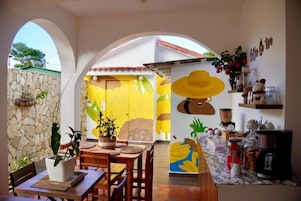 Uma sala de jantar com parede de pedra, mobiliário de madeira e um mural colorido.