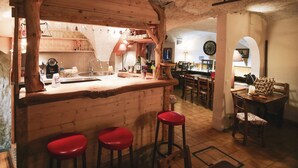 Uma cozinha rústica com banquetas de madeira, uma pia e diversos utensílios de cozinha.