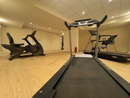 Uma academia com esteira, elíptico e bicicleta ergométrica.