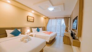 Quarto de hotel com duas camas, televisão e varanda com cortinas.