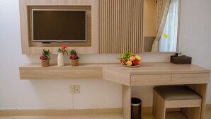 Casa de banho moderna com toucador de madeira, televisão fixada na parede e espelho.