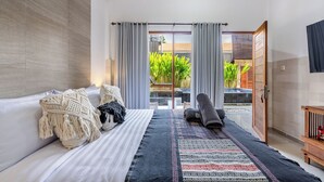 Quarto moderno com cama, vista para um jardim e porta deslizante para área externa.
