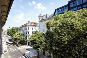 Vista da rua com um elétrico, edifícios históricos e árvores.