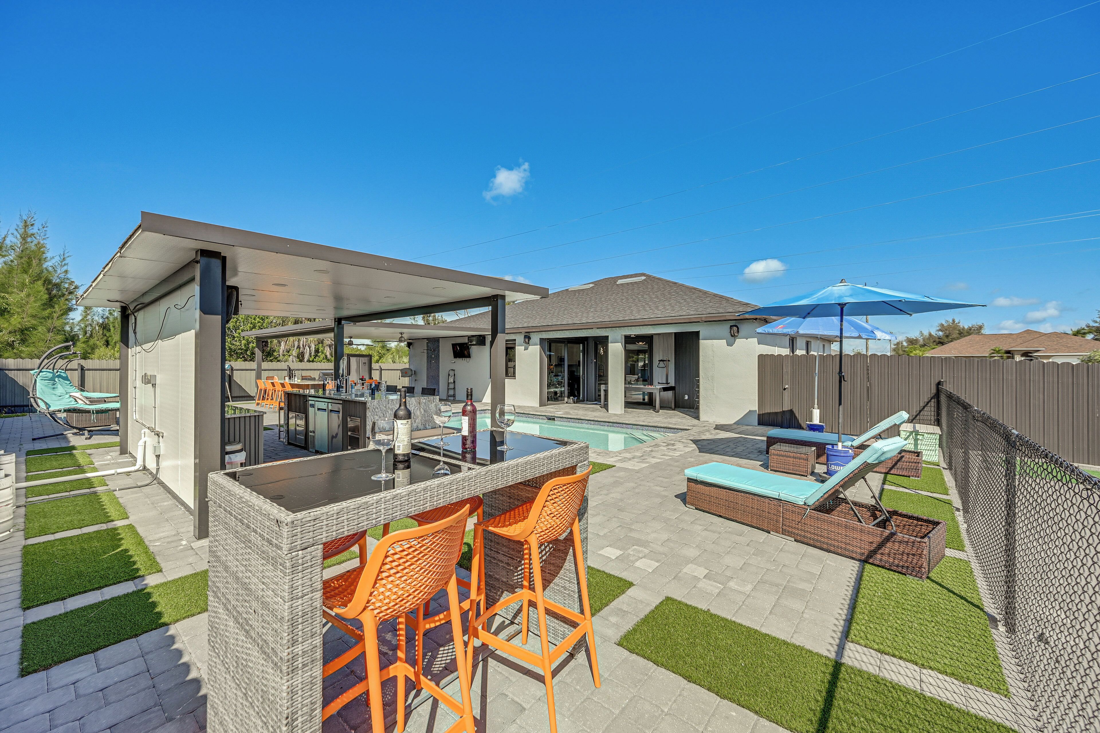 Um pátio externo moderno com piscina, bar e área de estar.