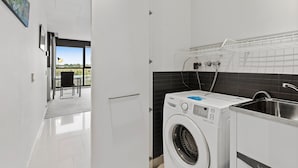 Uma lavanderia moderna com máquina de lavar, varal e vista para o exterior.