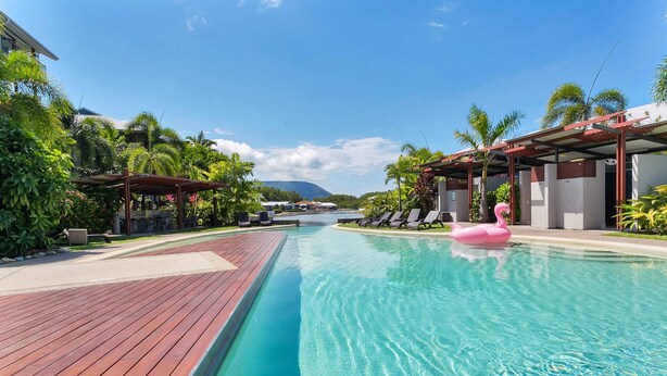 Uma piscina com um deck de madeira, cadeiras de descanso e um boi de flamingo flutuante.