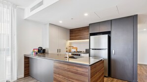 Cozinha moderna com ilha central, eletrodomésticos de aço inoxidável e armários de madeira.