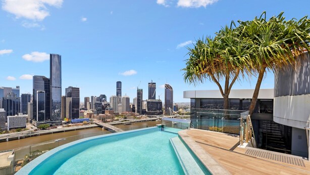 Piscina no terraço com vista para o horizonte urbano, uma palmeira e uma estrutura de edifício moderna.