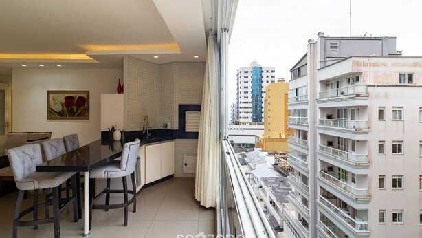 Um apartamento moderno com área de jantar, cozinha e grandes janelas com vista para a paisagem urbana.