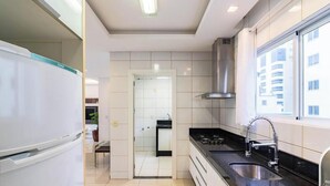 Cozinha moderna com geladeira, fogão e pia.