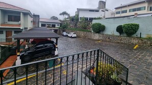 Um bairro residencial com um pátio pavimentado, uma garagem coberta e um muro de pedra.