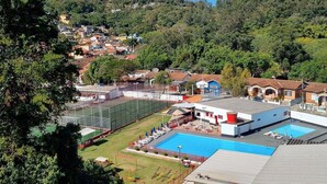 Uma área residencial com casas, piscina e campo esportivo cercado.