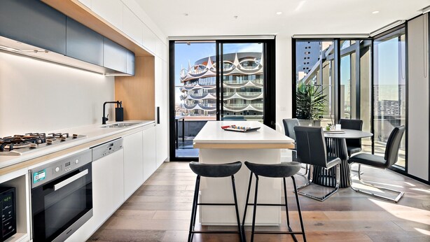 Cozinha moderna com ilha central, banquetas e área de refeições com mesa e cadeiras.