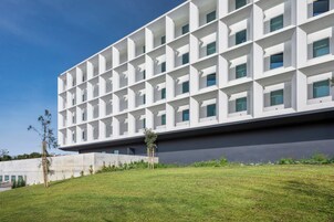 Um edifício moderno com fachada em grade, várias janelas e telhado plano.