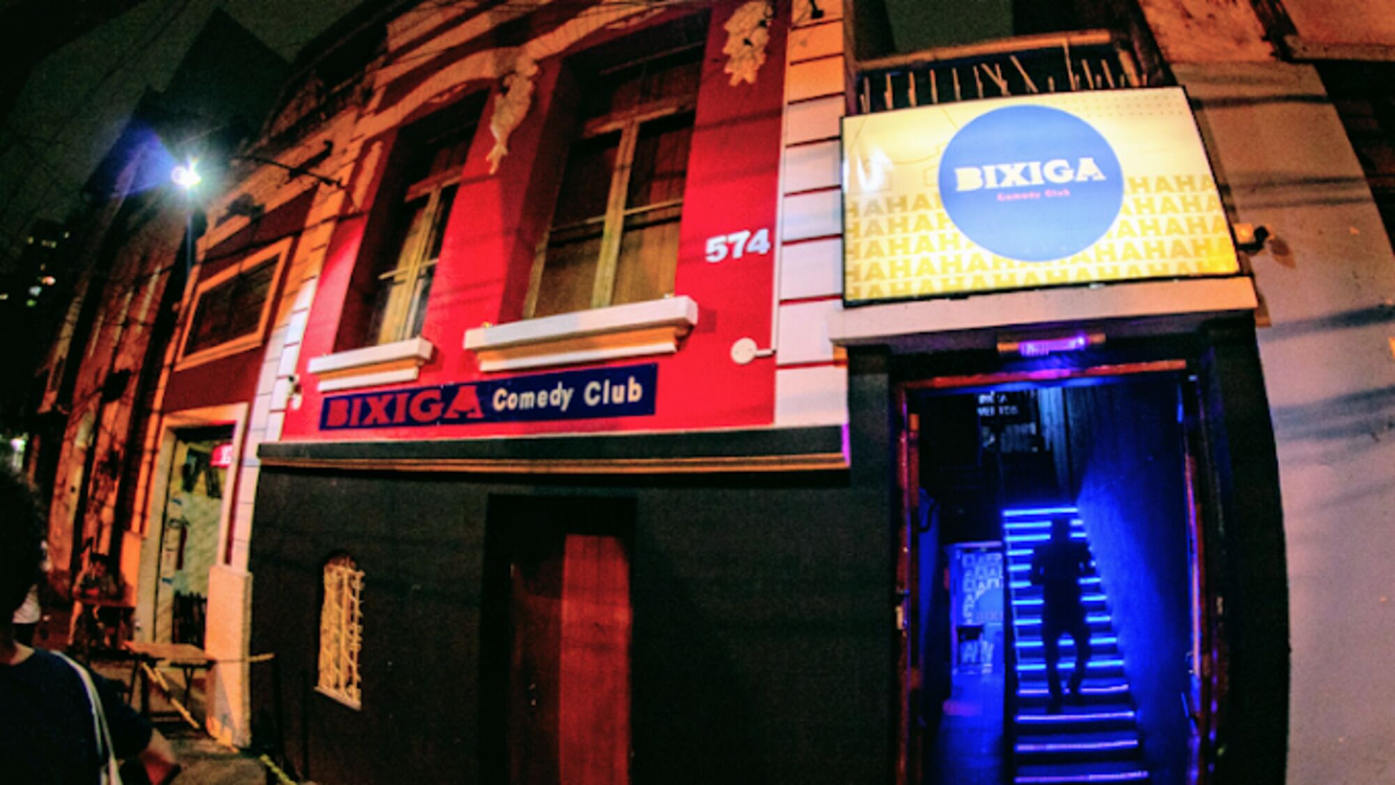 Um edifício com uma placa indicando 'BIXIGA Comedy Club' e o número '574' na fachada.