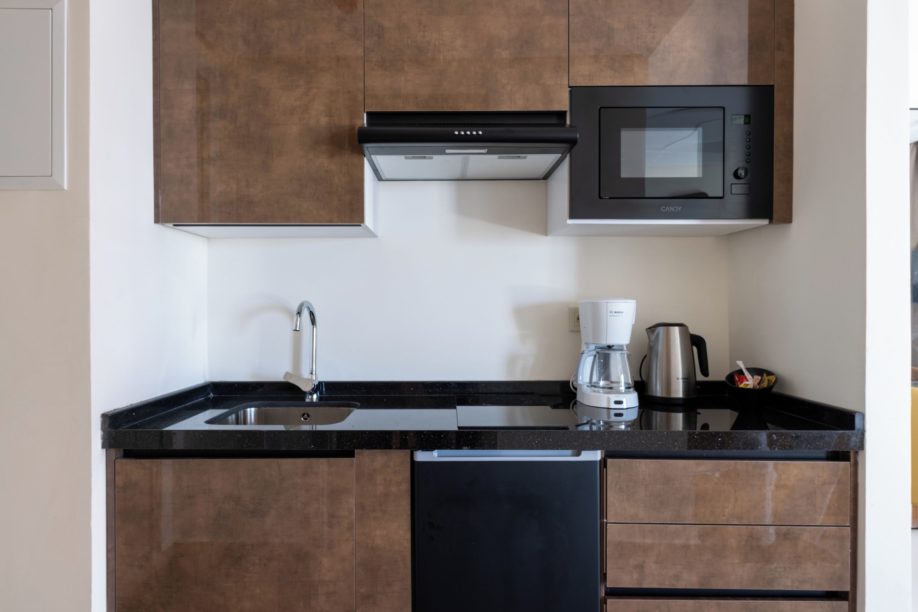 Uma cozinha moderna com micro-ondas, cafeteira e máquina de lavar louça embutidos.