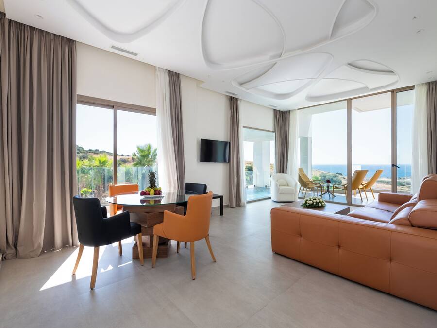 Uma sala de estar moderna com sofá, mesa de jantar, cadeiras e televisão.