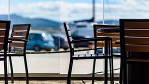 Two chairs with "KELER" signs, a glass window, and a view of parked cars and mountains.