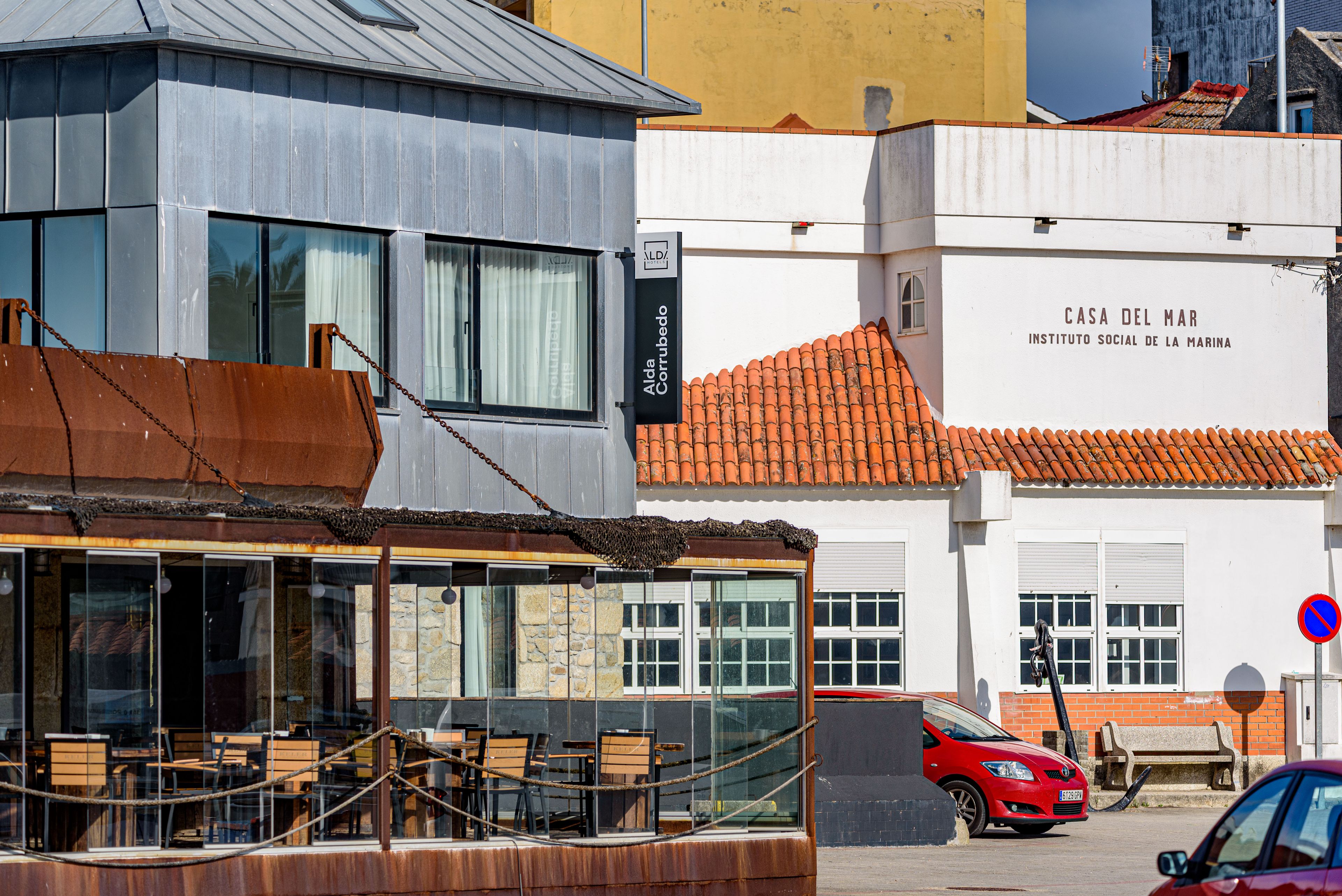 Um edifício com uma placa indicando 'Casa del Mar' e um carro vermelho estacionado na frente.