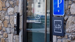 Um muro de pedra com um sinal de estacionamento e uma porta com teclado numérico e uma placa indicando