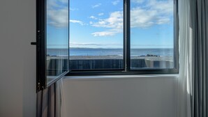 Quarto com uma grande janela com vista para a praia.
