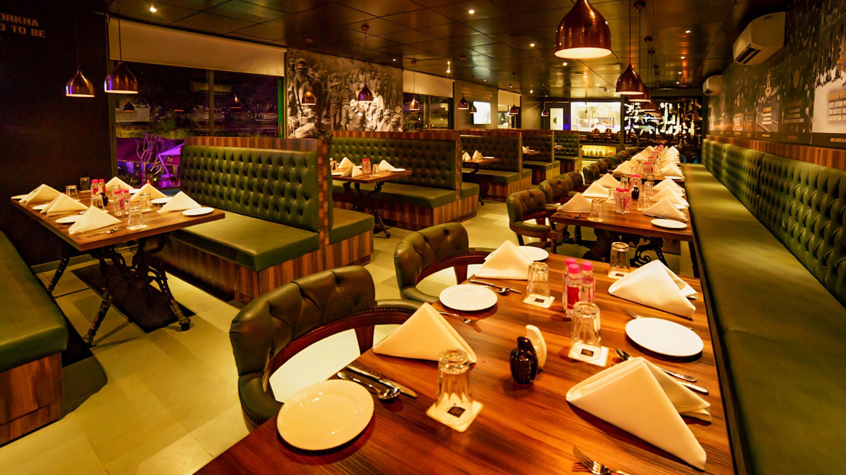 Restaurante com cabines e mesas, cada conjunto com pratos, talheres e acompanhamentos.