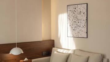 Quarto de hotel moderno com cama, sofá, mesa de cabeceira e obra de arte na parede.
