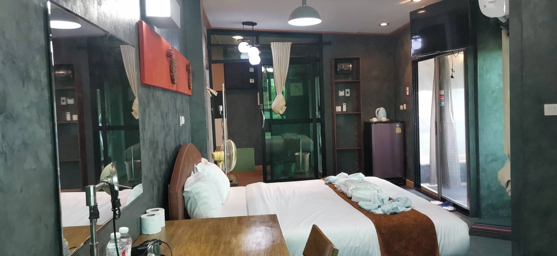 Quarto de hotel moderno com uma cama grande, uma escrivaninha de madeira, um espelho e uma janela ampla com vista.
