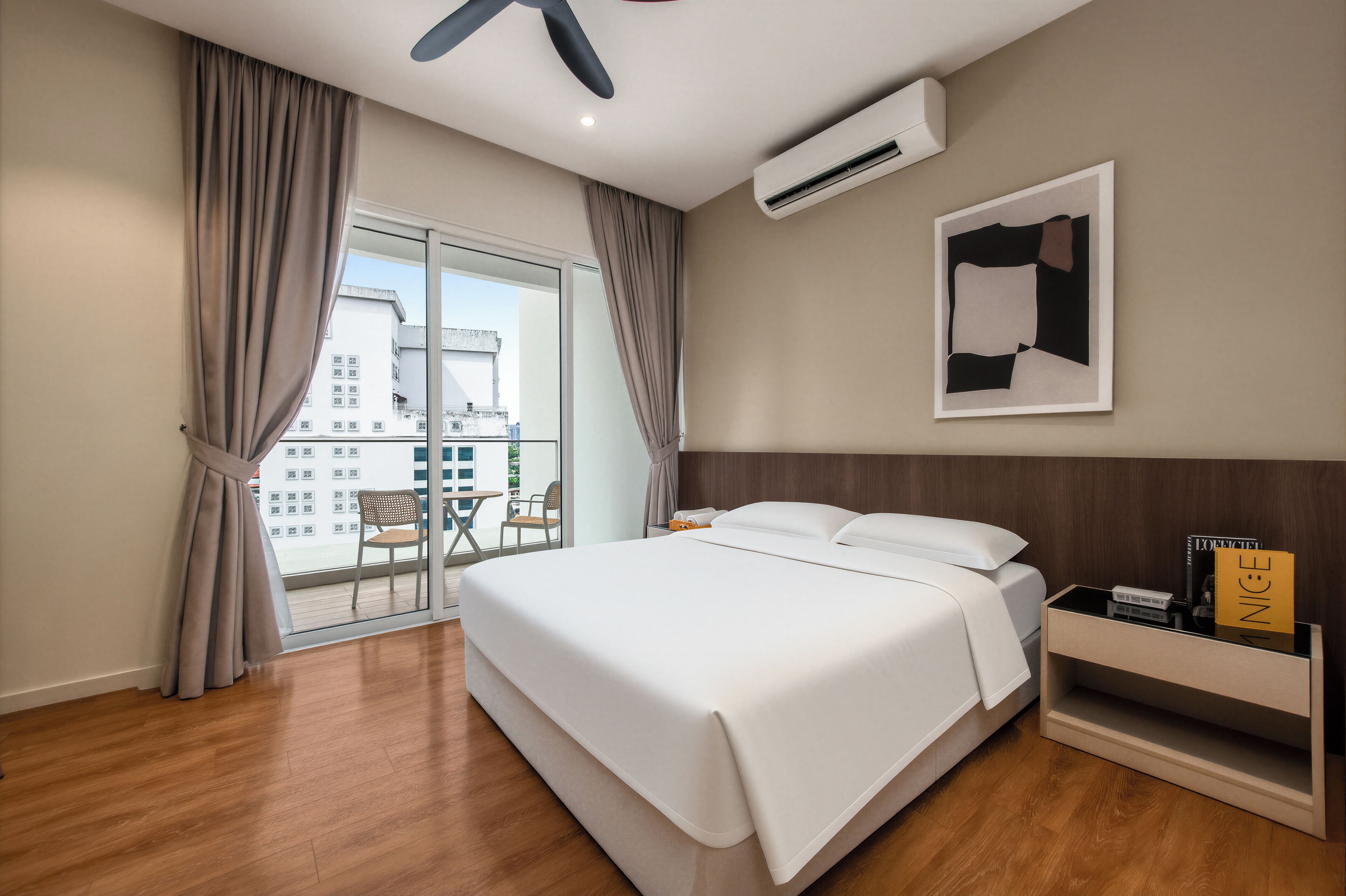 Quarto de hotel com cama, mesa de cabeceira, janela com cortinas, ar condicionado fixado na parede e vista para a cidade.