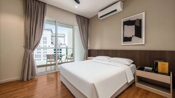 Quarto de hotel com cama, mesa de cabeceira, janela com cortinas, ar condicionado fixado na parede e vista para a cidade.
