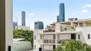 Um edifício moderno com várias varandas, grandes janelas e vista para o horizonte urbano com arranha-céus.