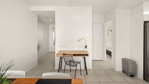 Um espaço de estar moderno e minimalista com uma mesa de jantar de madeira, uma cadeira de malha preta e uma pequena orquídea em vaso.