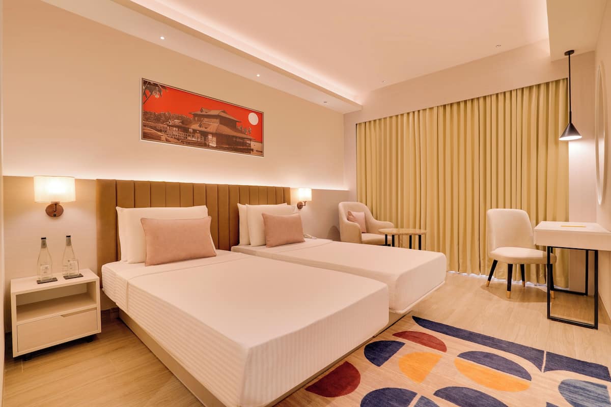 Quarto de hotel com duas camas, uma escrivaninha, uma cadeira, um criado-mudo e um quadro pendurado na parede.