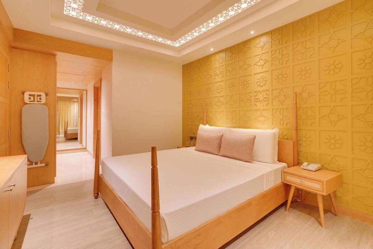 Quarto moderno com cama de madeira, mesa de cabeceira, espelho e parede estampada.