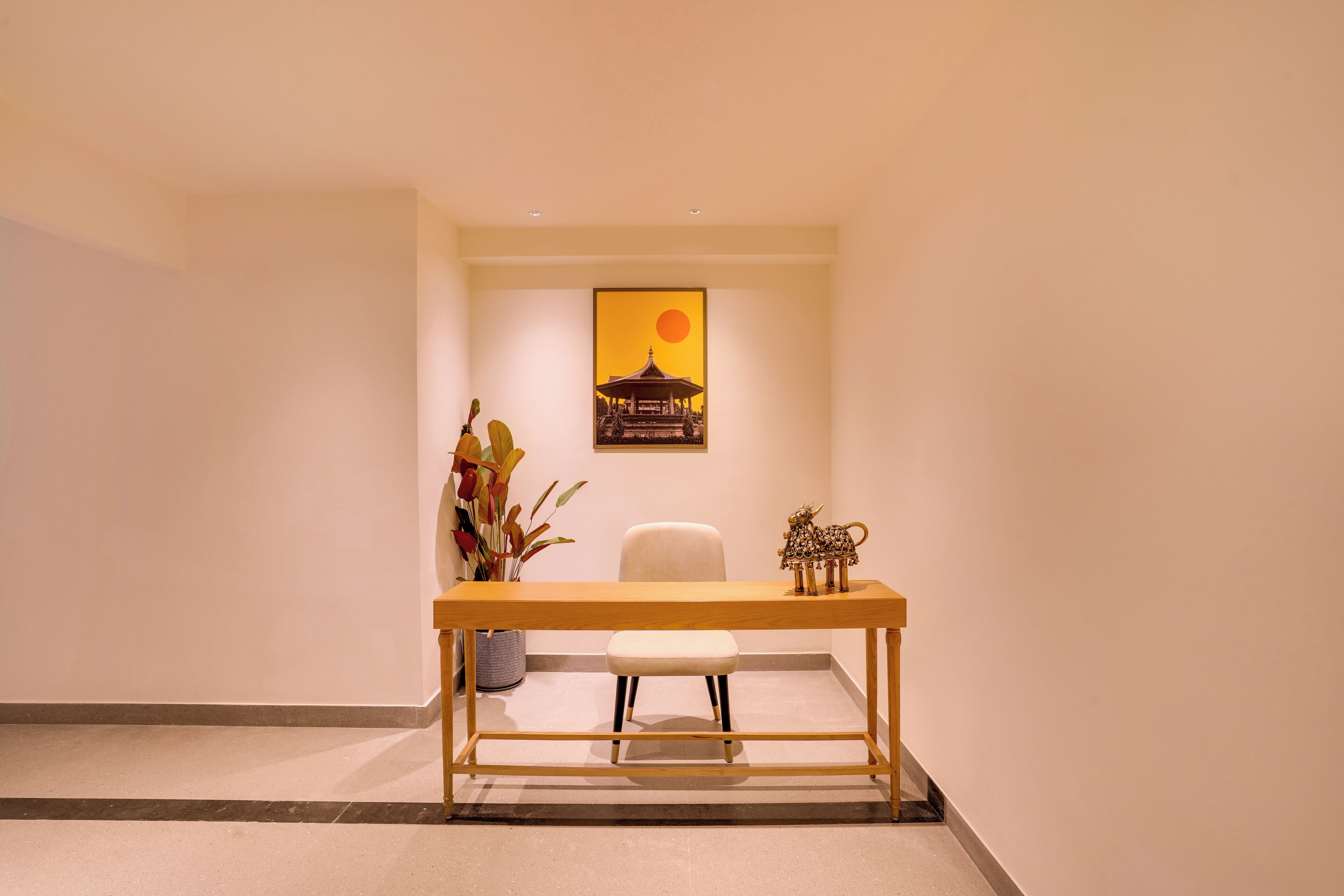 Uma área de recepção com uma mesa de madeira, uma cadeira branca e uma pintura de um pagode pendurada na parede.