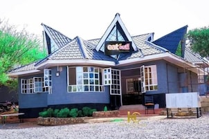 Um edifício com telhado pontiagudo e uma placa com a inscrição 'eat out!'.