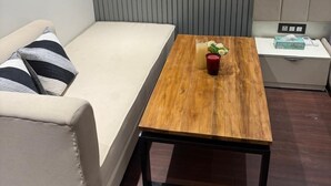 Quarto moderno com sofá, mesa de centro de madeira e um pequeno armário.