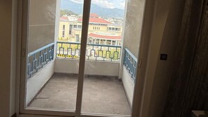 Quarto com uma grande porta de vidro deslizante que dá para uma varanda com vista para prédios e montanhas.
