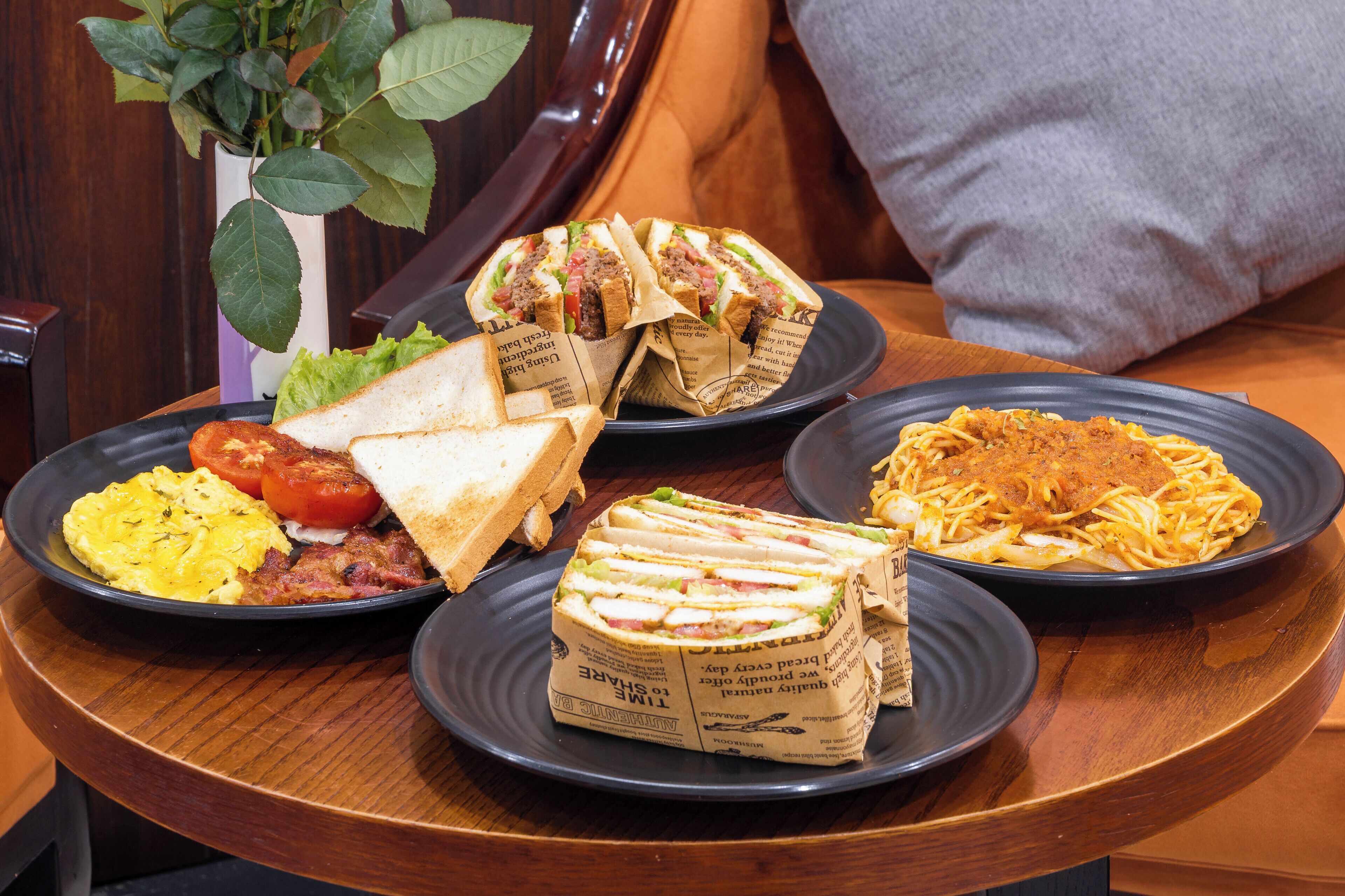 Uma mesa com diversos alimentos, incluindo sanduíches, ovos e massa.